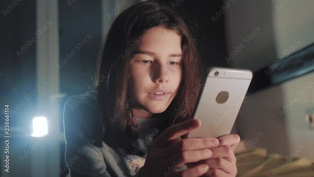 Teenage girl online shopping looks on her smartphone lifestyle in bed ...