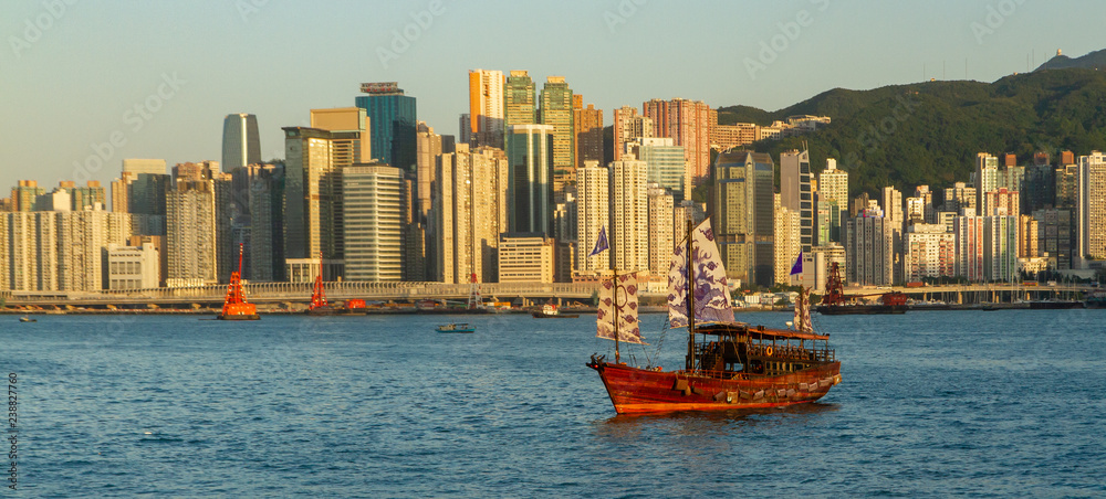 Traditional red Chinese Junk boat sailing in front of Hong Kong skyline ...