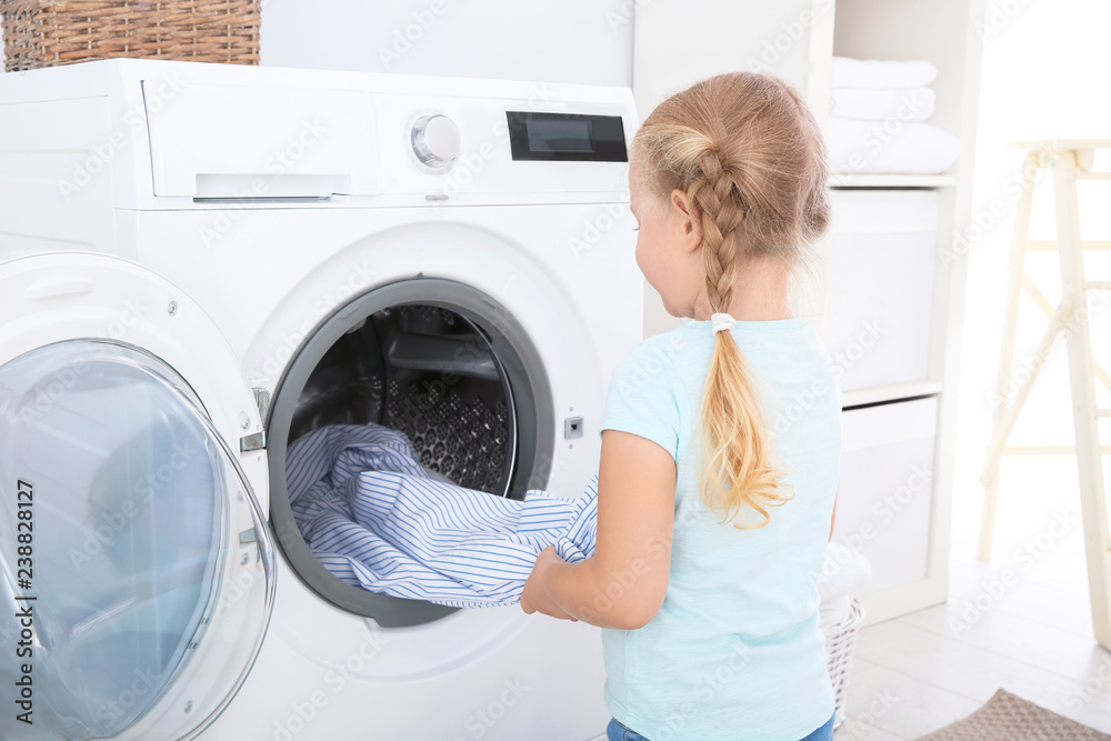 Photo & Art Print Adorable little girl doing laundry at home, New Africa