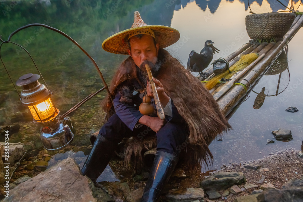 Foto de Chinese cormorant fisherman on raft in lake with a lighted ...