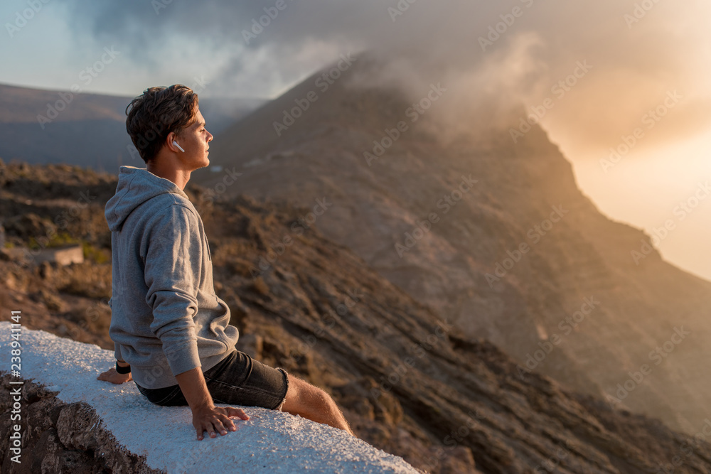 Young handsome guy enjoying of beautiful landscape view, sitting on the ...