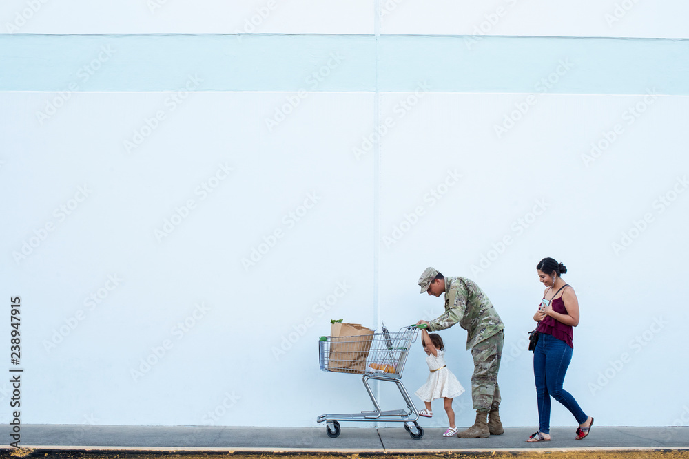 Soldier helping his daughter push a shopping cart Stock Photo | Adobe Stock