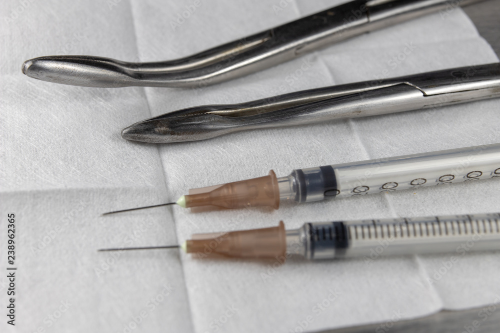 Sterile swab, pliers and a medical syringe on a hospital table ...