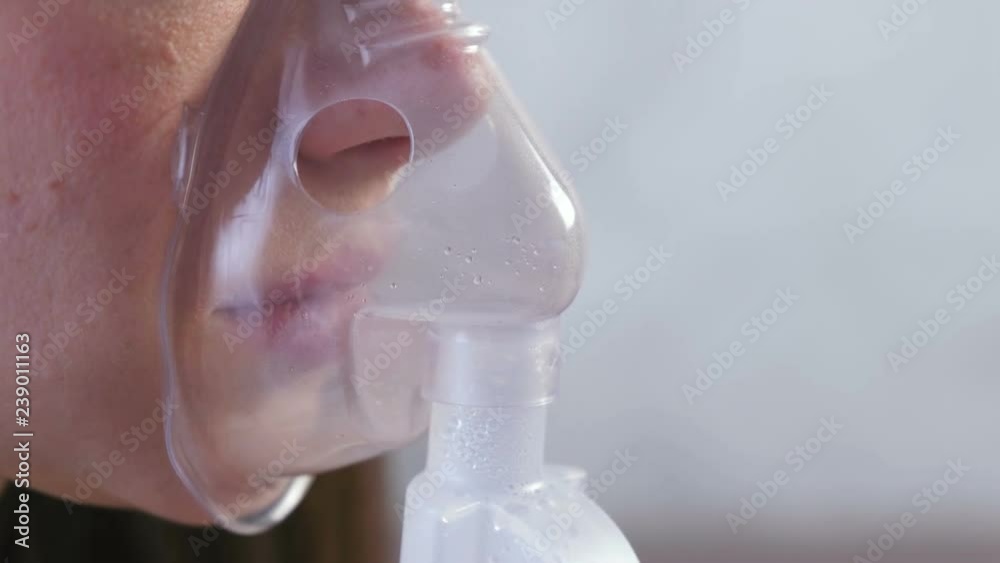 Use nebulizer and inhaler for the treatment. Young woman inhaling ...