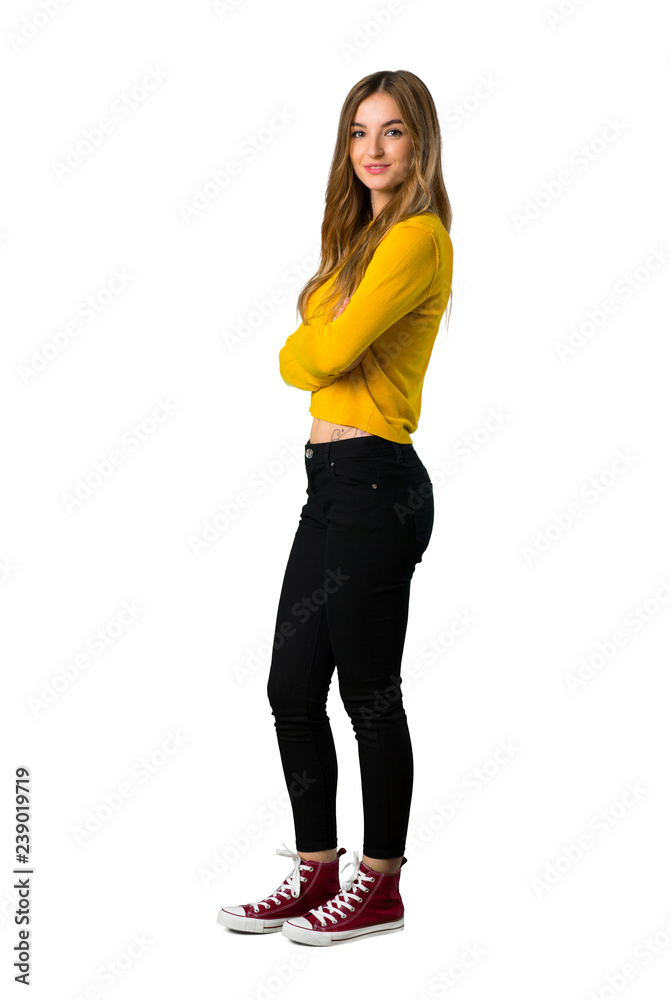 A full-length shot of a young girl with yellow sweater keeping the arms ...