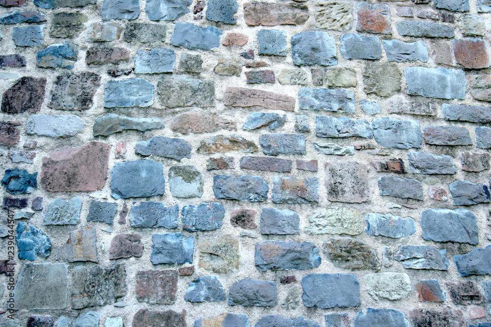 Mauer aus Naturstein in grau blau bis rot mit Fugen aus hellem Mörtel ...
