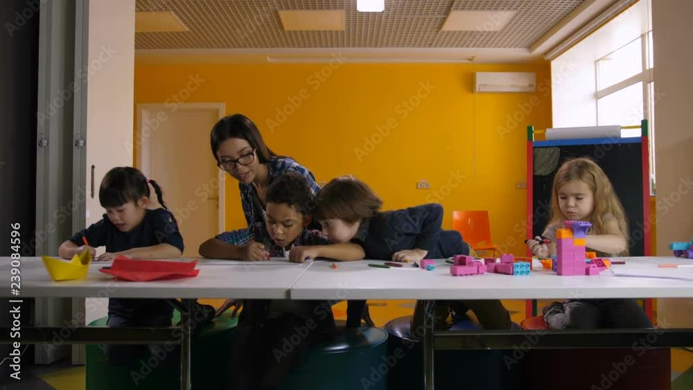 Vidéo Stock Positive preschool female teacher looking at diverse ...