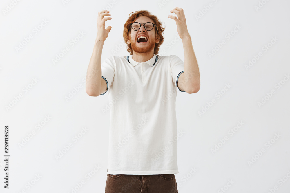 Indoor shot of upset redhead man in despair screaming and yelling from ...