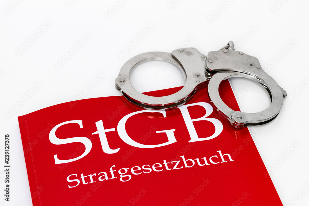 Strafgesetzbuch mit Handschellen Stock-Foto | Adobe Stock