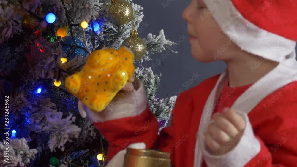 Happy child Dressed in Santa Claus costume, pulls yellow pig toy out of ...