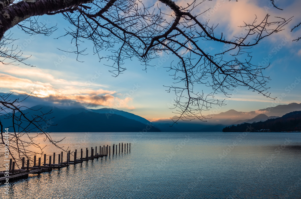 beautiful sunset view of lake Chuzenji with pier, tree and mountains ...