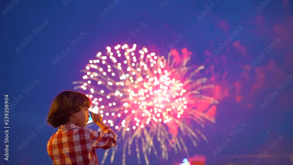 Little boy child filming pictures of beautiful fireworks in night sky ...