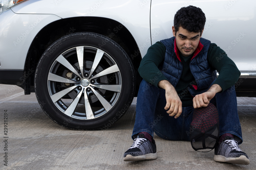 depressed man sitting on a ground leaning on his broken car. Sad, angry ...