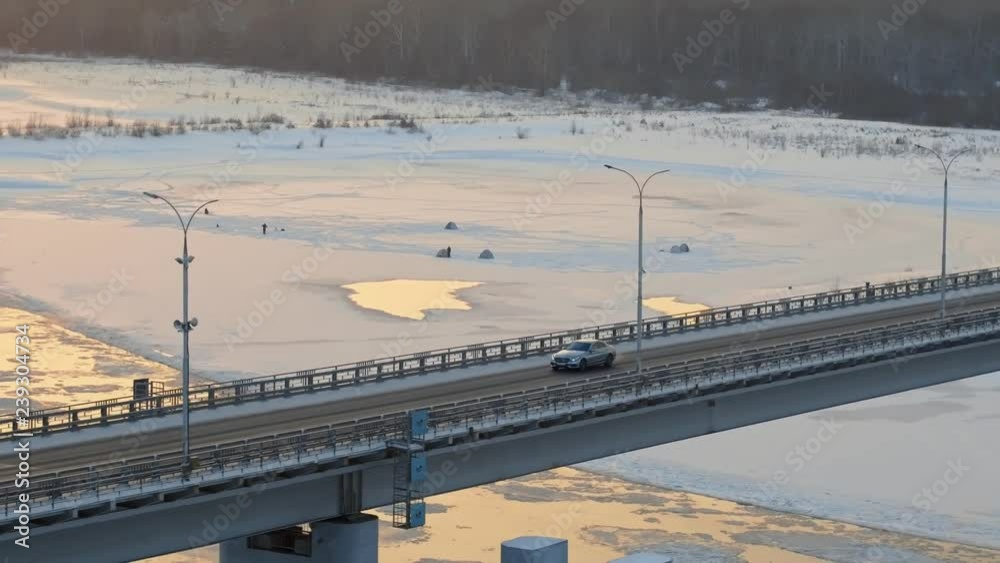 Aerial Tracking Alone Car crossing a Bridge Over winter River with ice ...