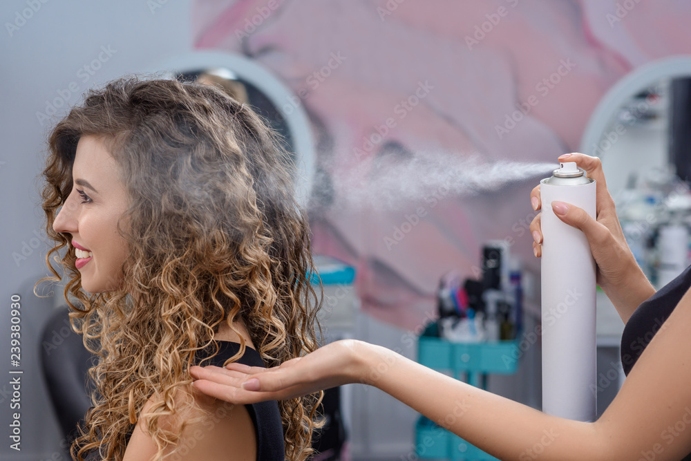 Stylist fixing hairstyle with hairspray in beauty salon Stock Photo ...