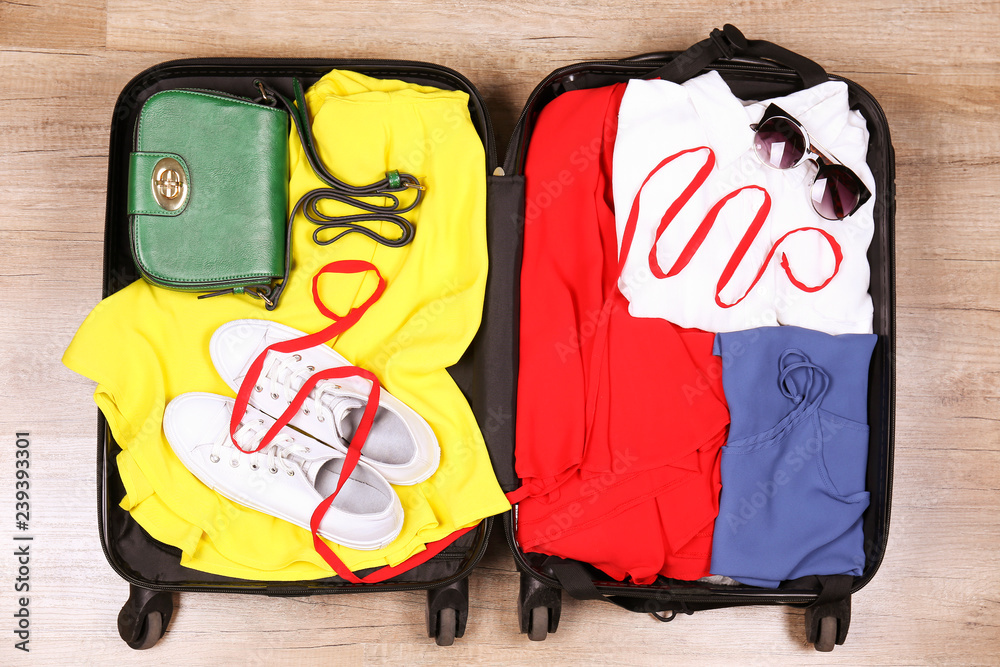 Open suitcase fully packed with folded women's clothing and accessories ...