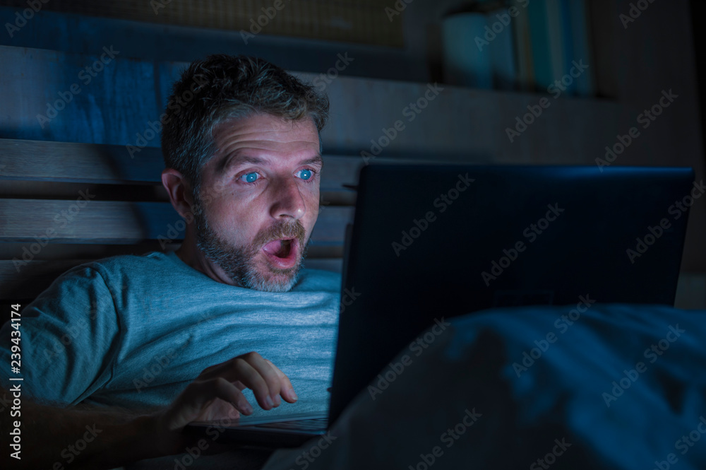 attractive internet addict man in shock and surprise networking late ...