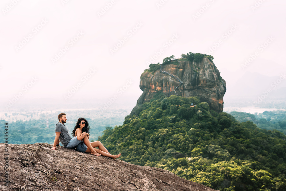 A couple in love on a rock admires the beautiful views. Boy and girl on ...