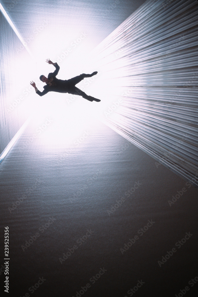 A conceptual silhouette of a businesman appearing to be falling down a ...