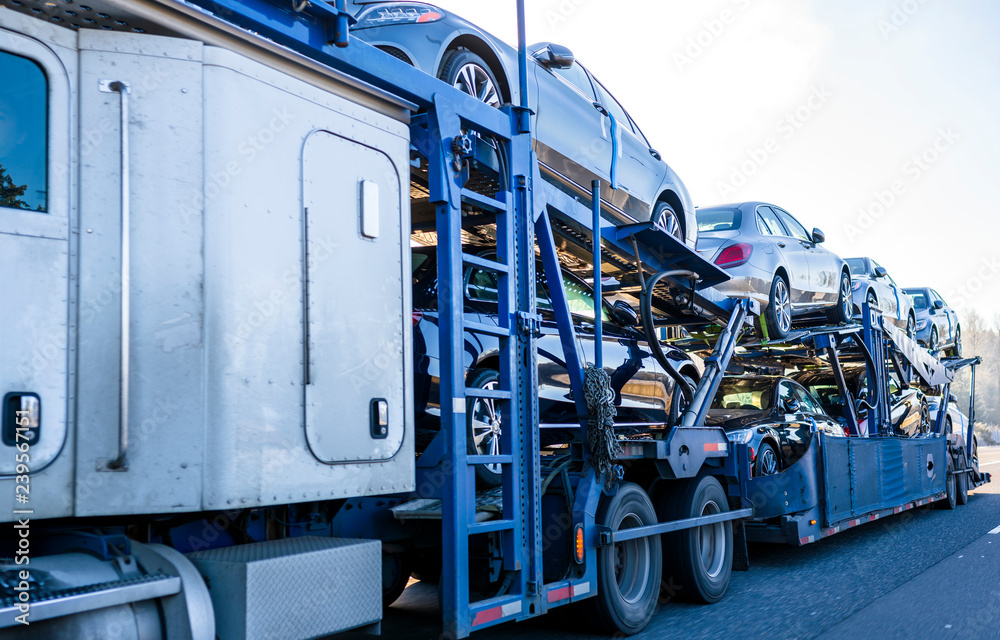 White big rig car hauler long distance semi truck transporting cars on ...