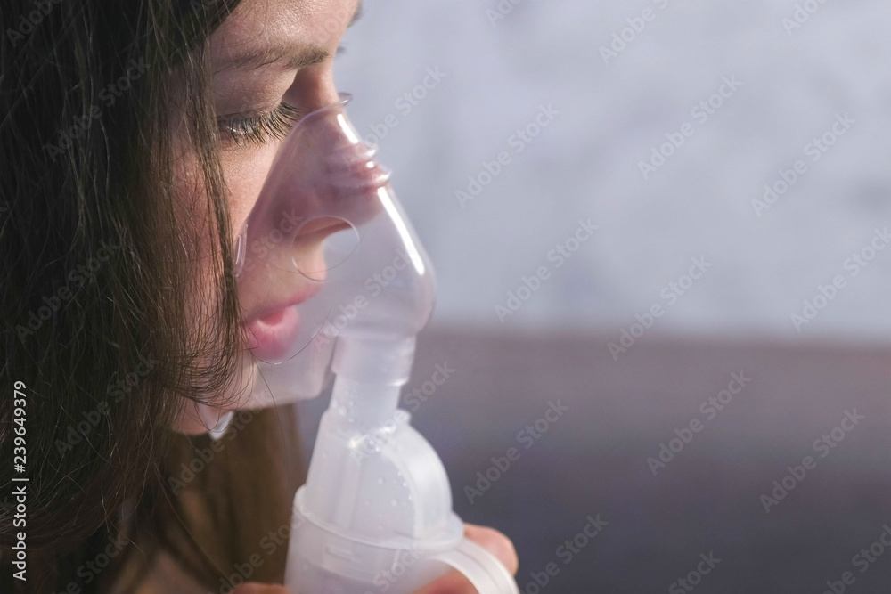 Use nebulizer and inhaler for the treatment. Young woman inhaling ...