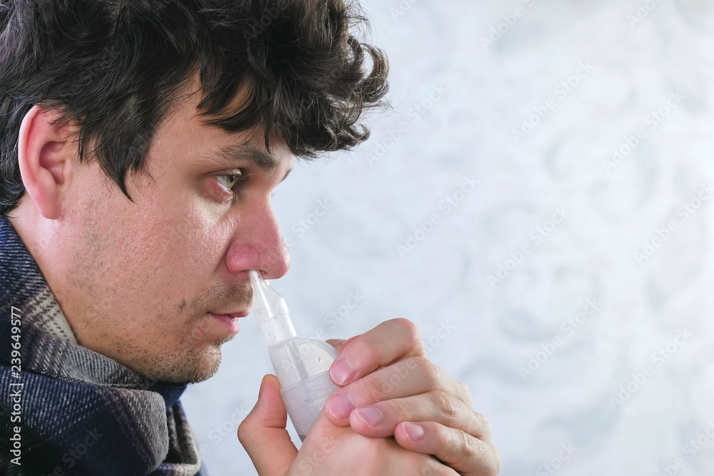 Sick man inhaling through inhaler nozzle for nose. Close-up face, side ...