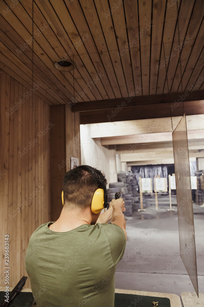 Man aiming with a pistol in an indoor shooting range Stock Photo ...