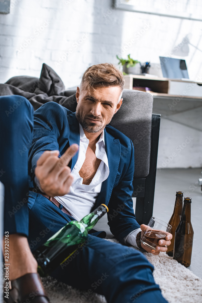 drunk businessman showing middle finger and holding glass with alcohol ...