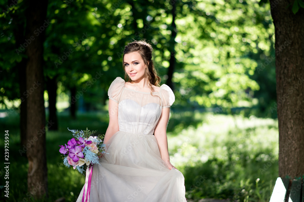 Stylish and beautiful bride walks in a flowered park with a wedding ...