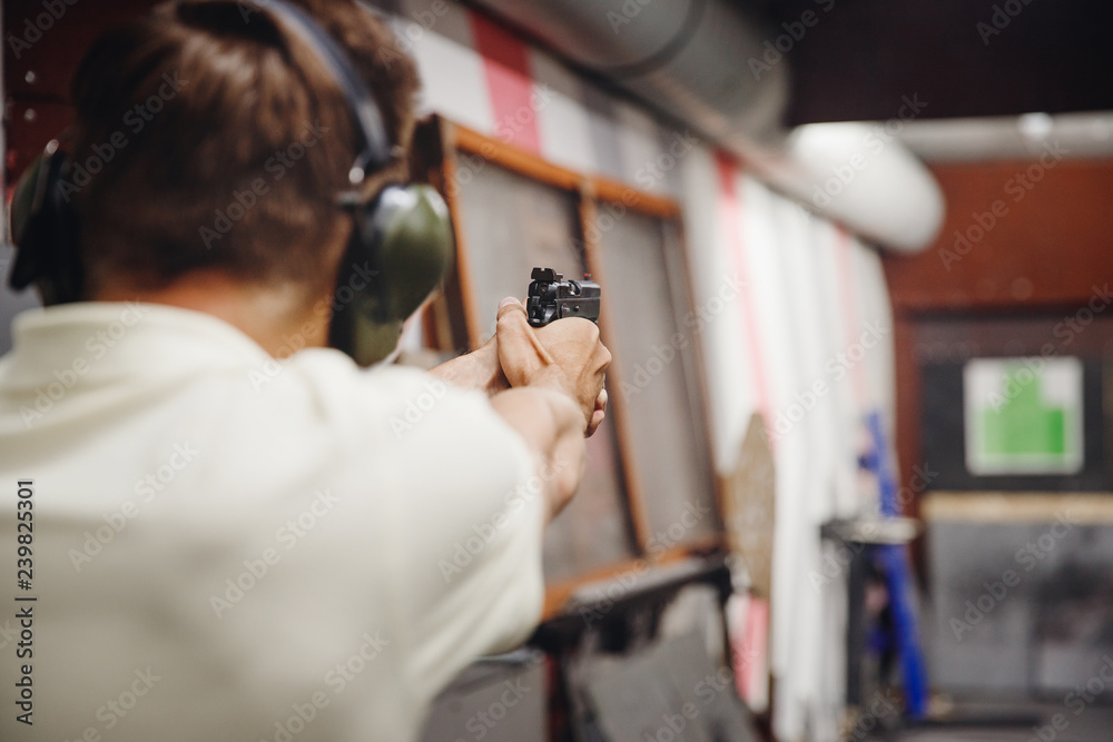 Shooting range gun. Man shoots pistol in noise protection headphones ...