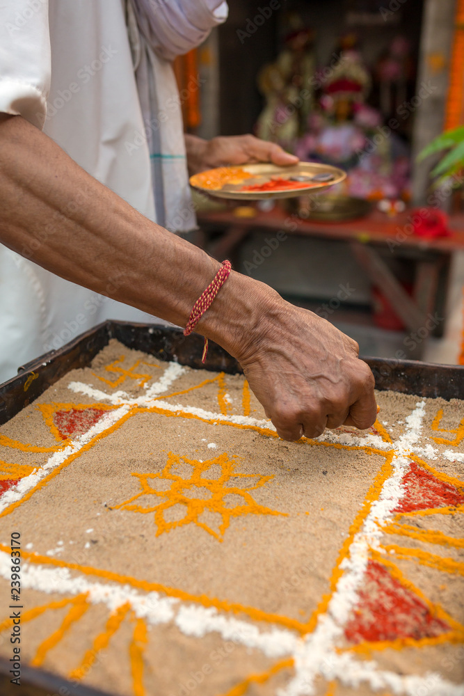 Hindu priest coloring traditional sand art (Rangoli) with religious ...