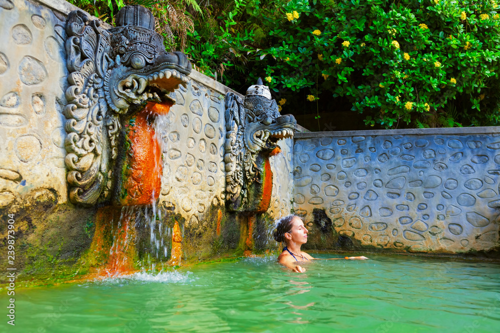 Young woman stand in thermal bath, relaxing under flowing water stream ...
