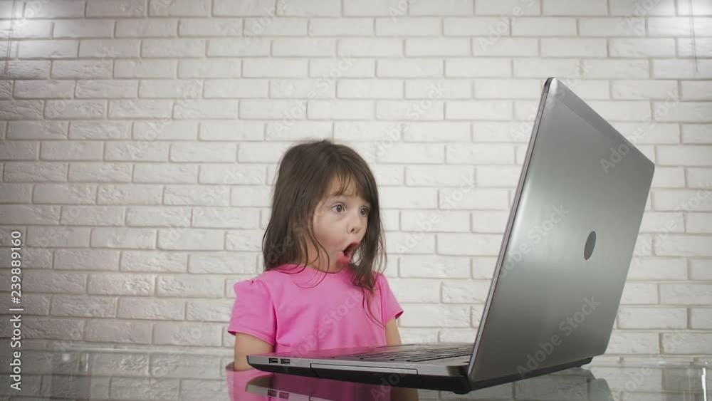 Shock children at the computer. The little girl is shocked by what she ...