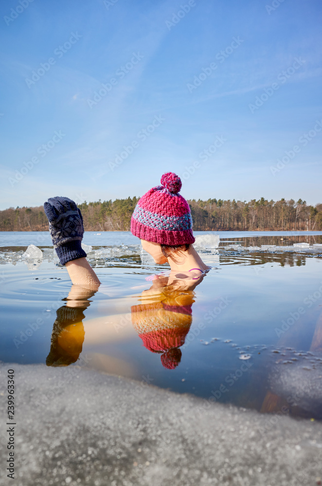 Fit woman performs ice swim in the ice hole. Holding hands above the ...