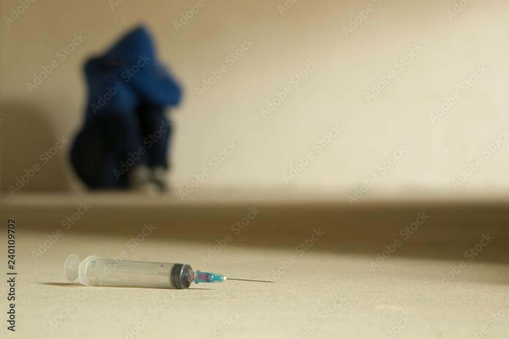 Drug addicted teenager sitting on the concrete floor in corner with ...