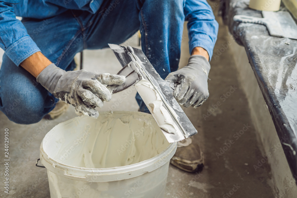 master is applying white putty on a wall and smearing by putty knife in ...