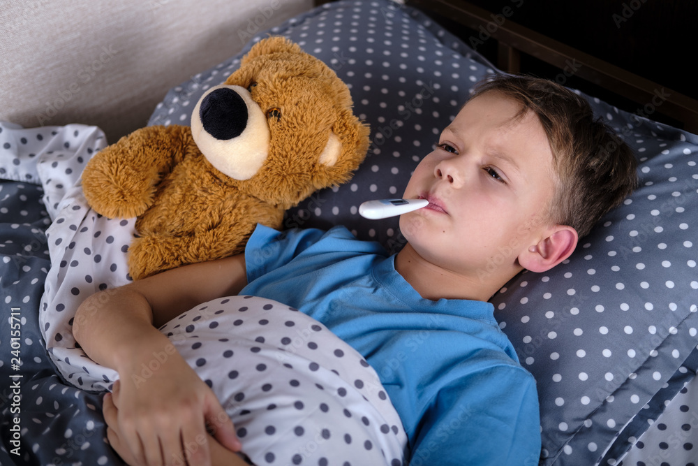 sick baby boy lying in bed with thermometer in mouth next to toy Stock ...