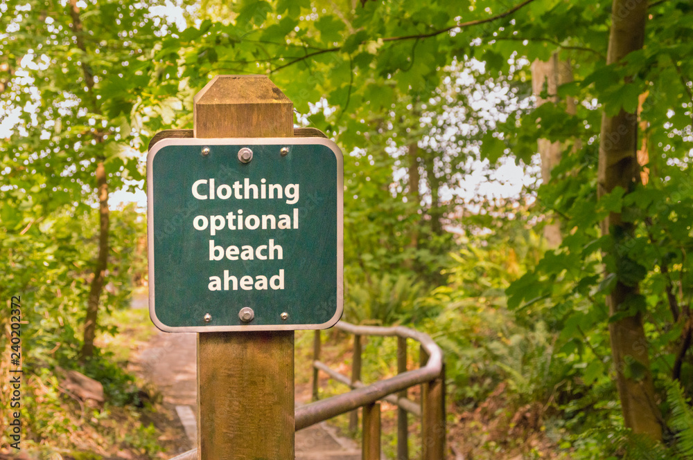 Clothing optional sign on post on trail to beach, British Columbia ...