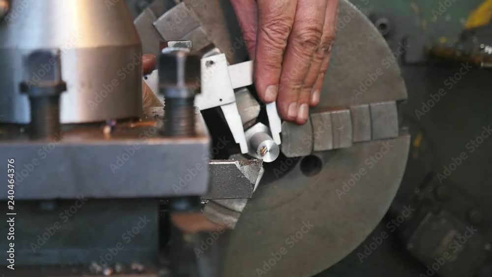 Callipers measuring the diameter of a metallic rod fixed to a lathe ...
