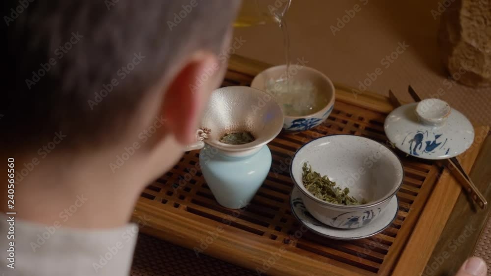 Tea master pouring infusion from fairness pitcher into bowl and ...