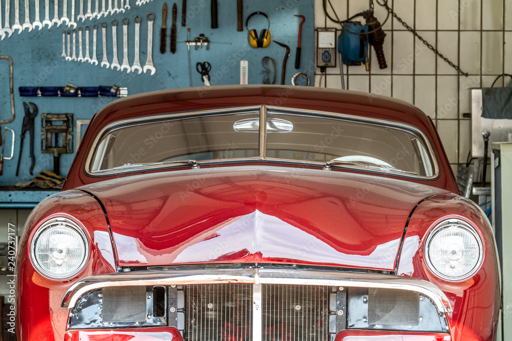 Foto de red oldtimer in a car repair shop in process in front of a wall ...
