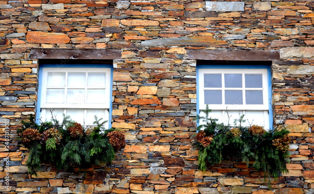 Rustic hand-hewn wood window set into a stone wall built from schist in ...