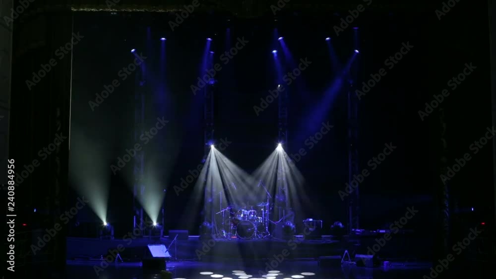 Blue light flashing and white rays on an empty stage in the dark. White ...