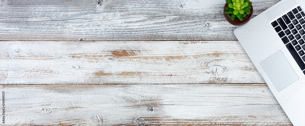 Overhead view of white rustic desk with laptop computer and small plant ...