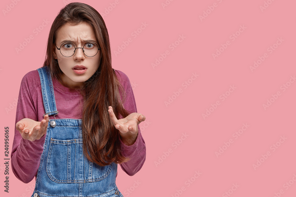 Indignant Caucasian woman looks angrily at camera, gestures with both ...