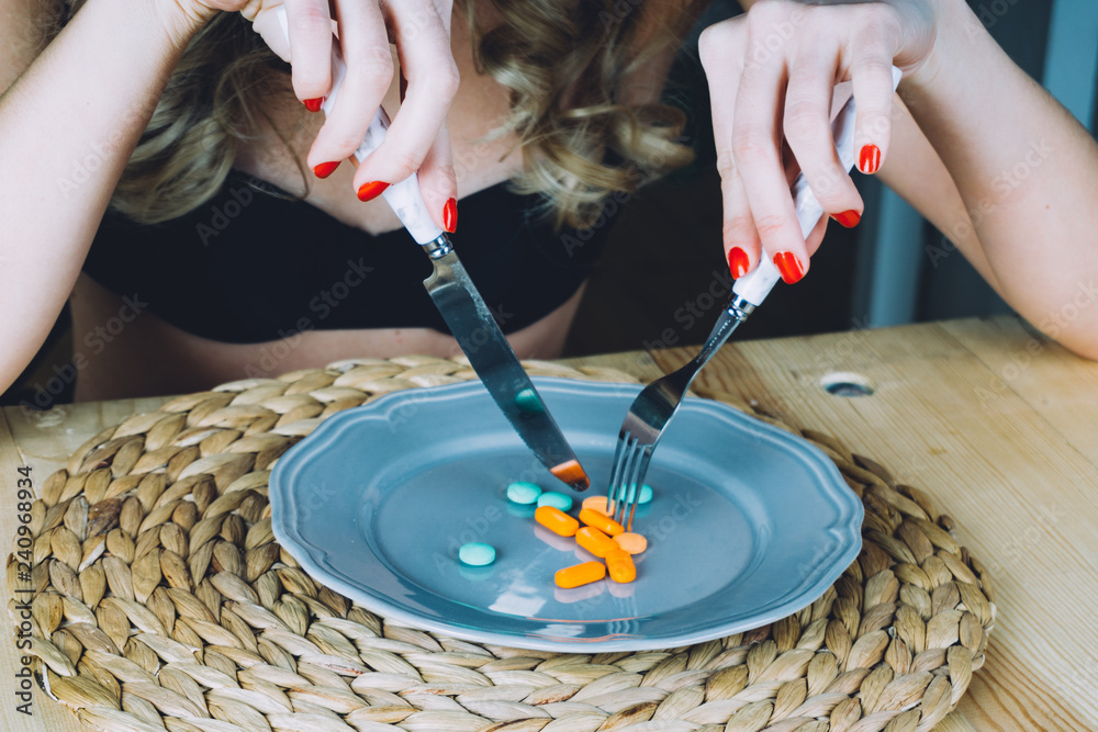 Beautiful young girl sits in the kitchen and eats pills. Model in ...