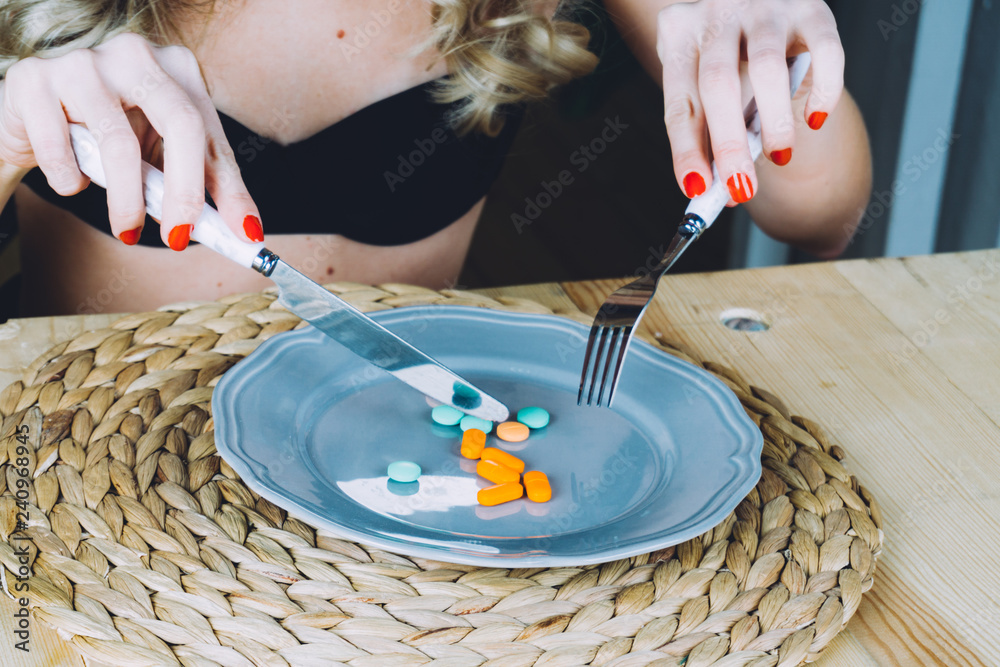 Beautiful young girl sits in the kitchen and eats pills. Model in ...