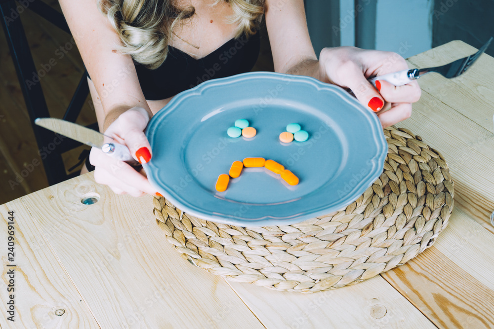 Beautiful young girl sits in the kitchen and eats pills. Model in ...