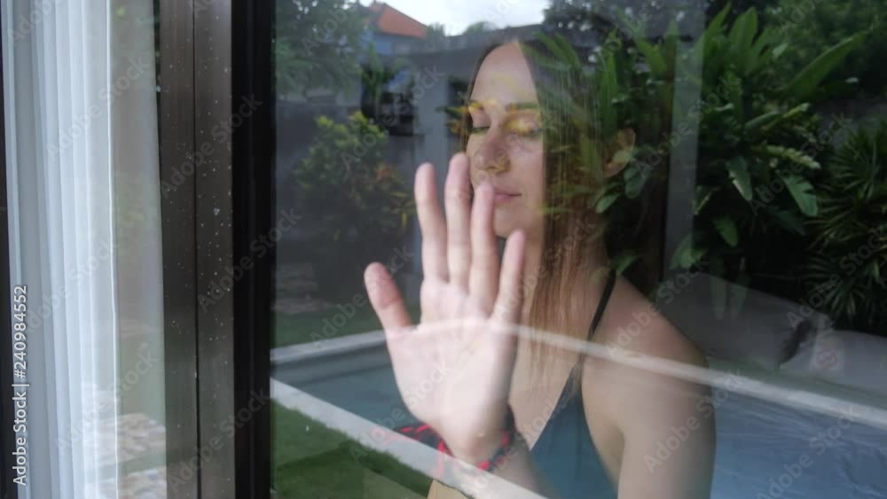 Woman looks out the window and says goodbye to someone, waving her hand ...