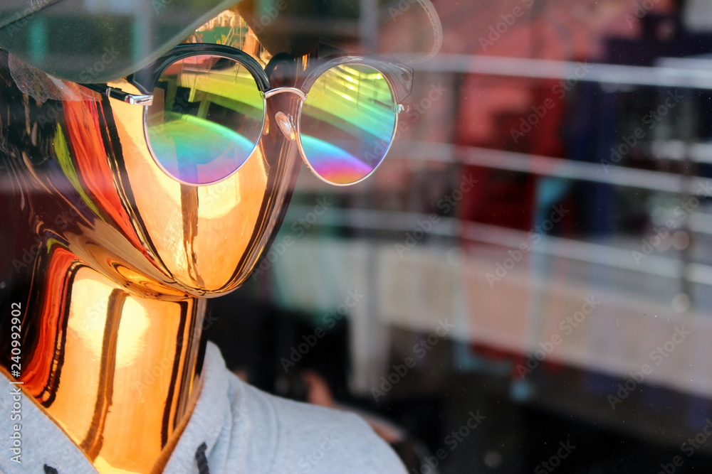 A reflective metallic gold mannequin wearing round sunglasses in a shop ...